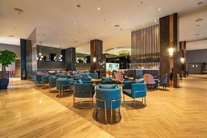 Um hall amplo com design moderno, com diferentes áreas de estar e um balcão de recepção.