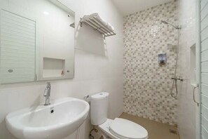 Casa de banho com lavatório branco, sanita e chuveiro.
