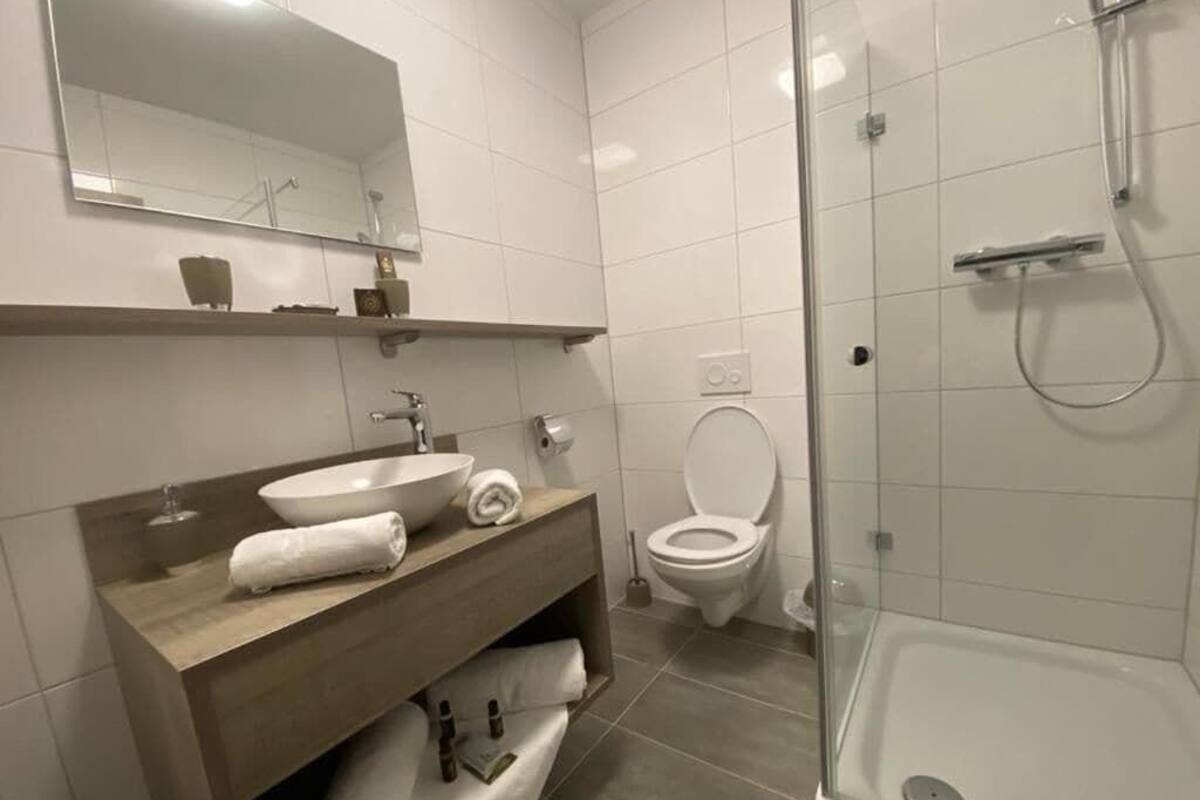 Uma casa de banho moderna com lavatório, sanita e chuveiro.