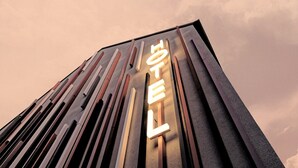 Um letreiro de hotel com ripas verticais e letras iluminadas que formam a palavra 'HOTEL'.