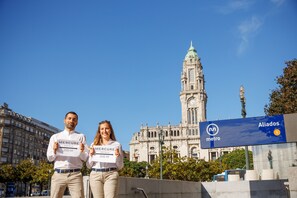 Duas pessoas segurando placas com a marca Mercure Hotels, com um sinal de estação de metrô ao fundo.
