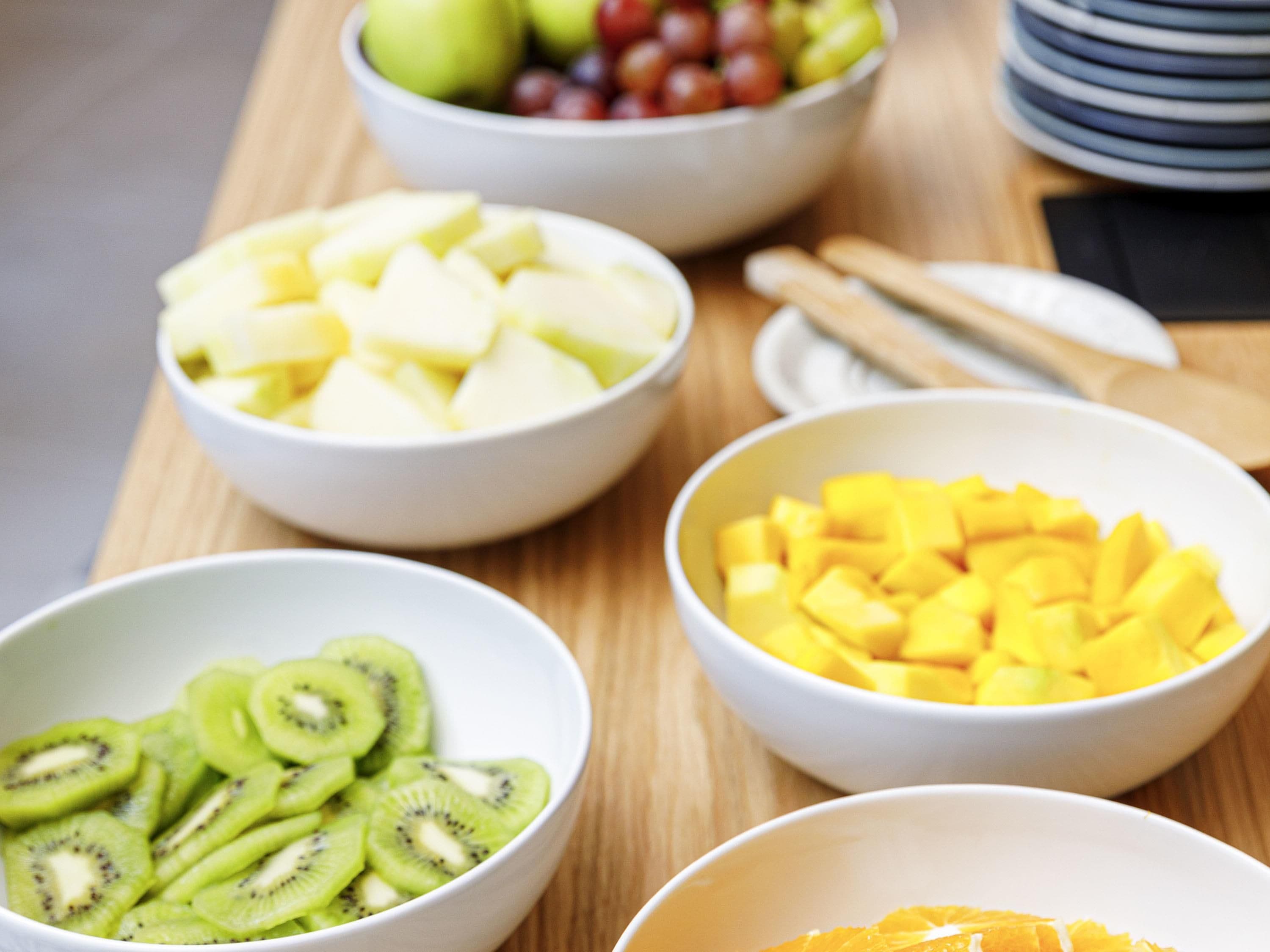 Tigelas com frutas fatiadas sobre uma mesa de madeira.