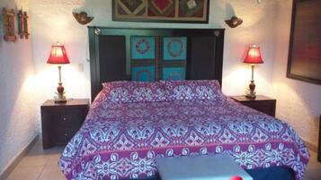 Quarto com uma cama, duas luminárias de cabeceira, um relógio de parede e um quadro emoldurado acima da cama.