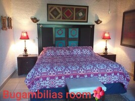 Quarto com uma cama, duas luminárias de cabeceira, um relógio de parede e um quadro emoldurado acima da cama.
