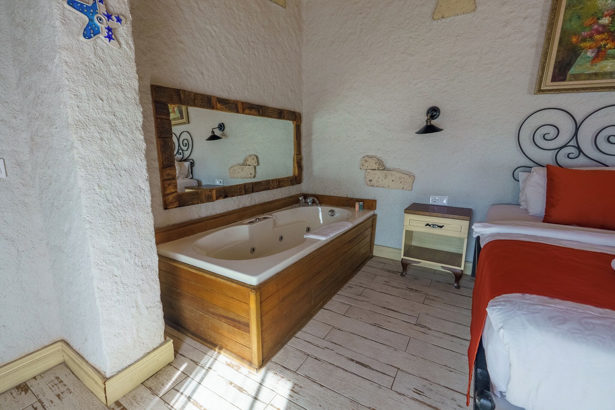 Casa de banho com banheira de madeira, toucador de madeira e cama com roupa de cama vermelha.