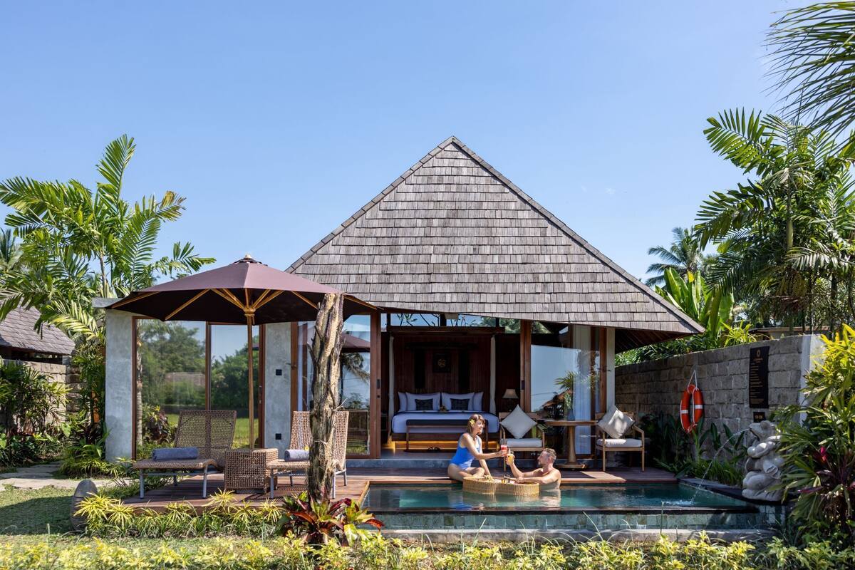 Resort com piscina, área de estar externa e espaço coberto com cama.
