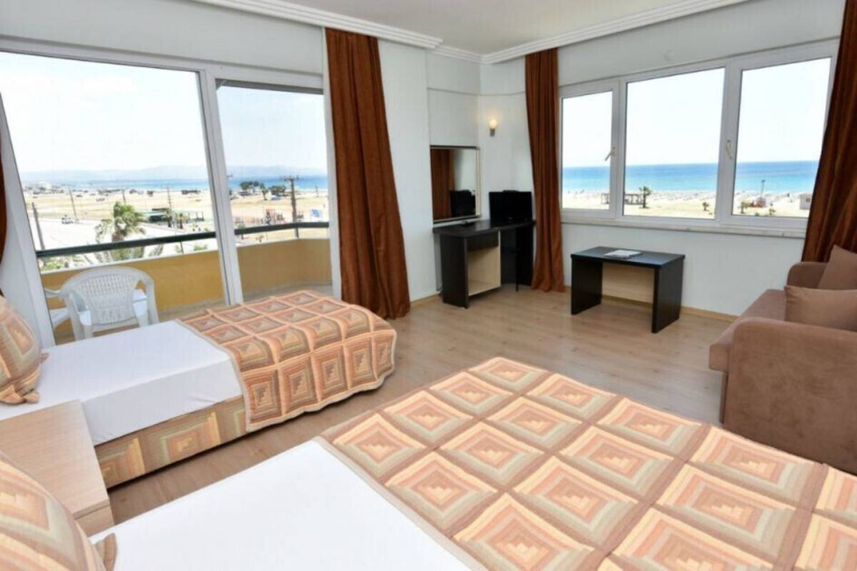 Quarto de hotel com varanda, uma cama, sofá, escrivaninha e televisão.