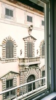 Fachada de edifício com janelas em arco, frontão central e detalhes em pedra decorativa.