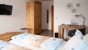 Quarto com cama, guarda-roupa de madeira, escrivaninha com abajur e decoração nas paredes.