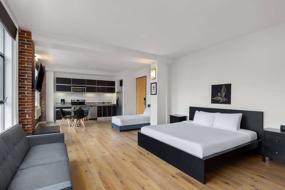 Quarto de hotel moderno com uma cama grande, um sofá, uma área de cozinha e uma mesa de jantar.