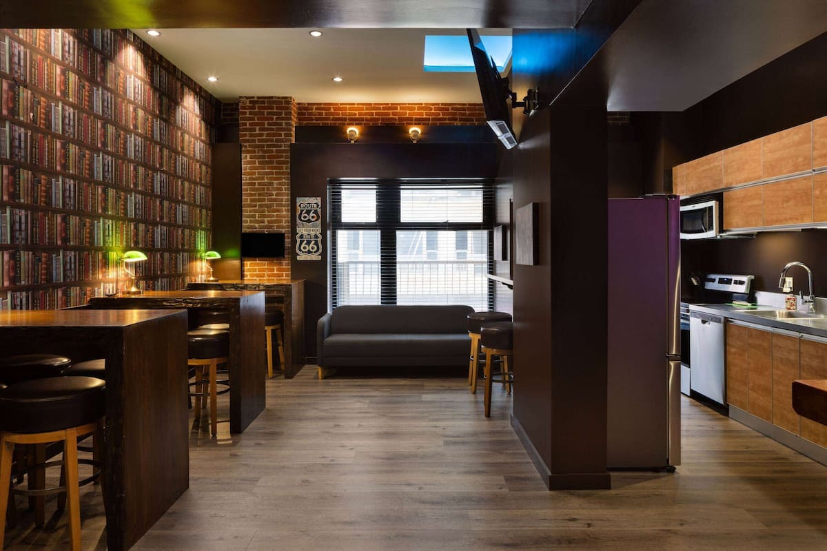 Uma cozinha moderna com frigorífico embutido, um espaço de bar com banquetas, uma estante e uma janela grande.