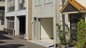 Um edifício residencial de vários andares com varandas, garagem e um pequeno jardim.