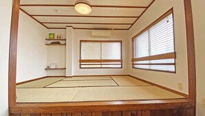 Um quarto japonês tradicional com piso de tatame, vigas de madeira e portas deslizantes shoji.