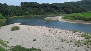 Um rio com margem rochosa e floresta densa ao fundo.