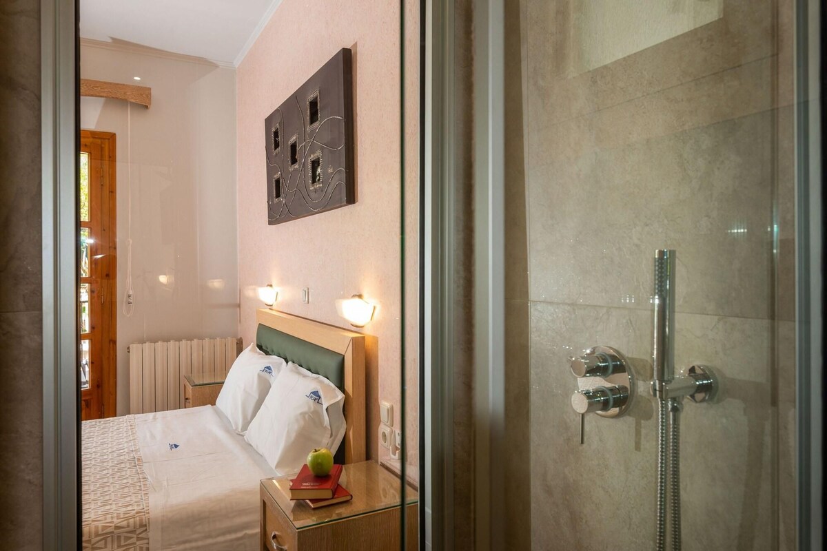 Quarto de hotel com cama, mesa de cabeceira e área de chuveiro.