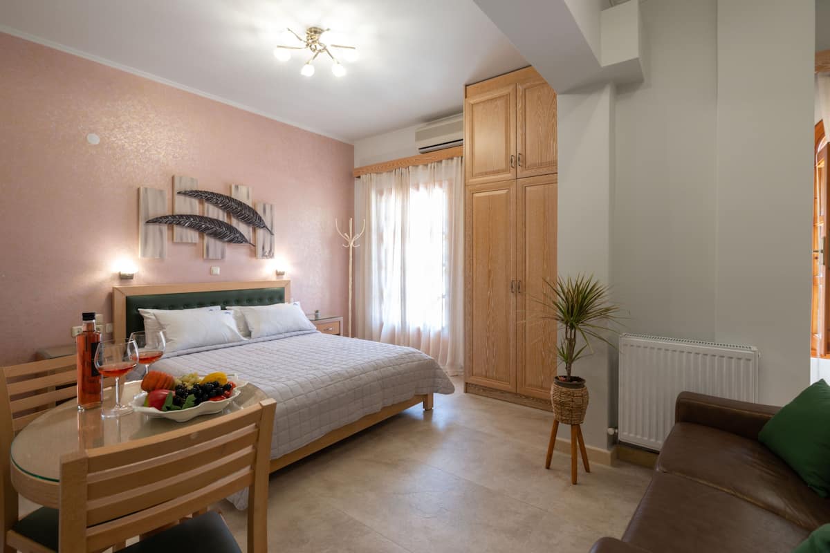 Quarto com cama, mesa de cabeceira e canto de refeições com cadeiras e uma mesa.