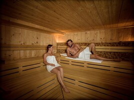 Uma sauna com bancos de madeira e parede de pedra.
