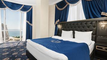 Quarto de hotel com uma cama grande, uma mesa de cabeceira e vista para o mar.