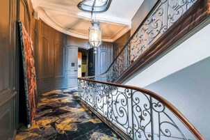 Uma escadaria imponente com grades de metal ricamente decoradas e piso estampado.