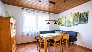 Uma sala de jantar com uma mesa de madeira, cadeiras, um banco e um armário.