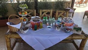 Mesa posta ao ar livre com diversos alimentos e bebidas.