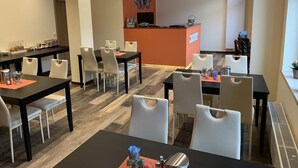 Uma sala de jantar de hotel com várias mesas e cadeiras, um balcão de recepção e um design de interiores moderno.