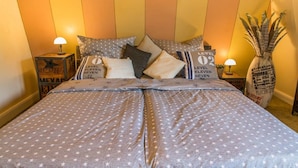 Cama com colcha estampada em formato de estrelas, várias almofadas e duas mesas de cabeceira com abajures.