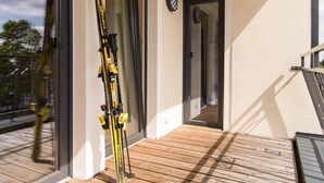 Um deck de madeira com um par de esquis encostados em uma porta de vidro.