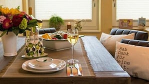 Uma mesa de jantar posta com pratos, talheres, um copo de vinho branco e um arranjo floral.