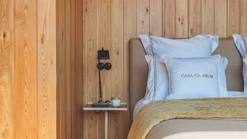 Um quarto com painéis de madeira, uma cama, almofadas, uma mesa de cabeceira e um abajur.