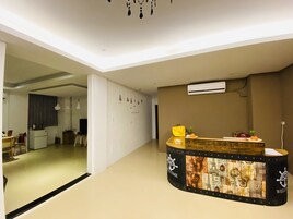 Um saguão de hotel moderno com balcão de recepção, área de refeições e unidade de ar condicionado na parede.