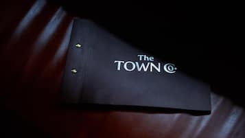 Uma pasta preta com o texto 'The TOWN' e um símbolo, colocada sobre uma superfície escura.