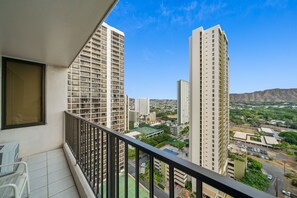 Varanda com vista para edifícios altos e uma cadeia montanhosa distante.