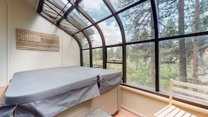Quarto com claraboia, uma cama e vista para uma floresta.