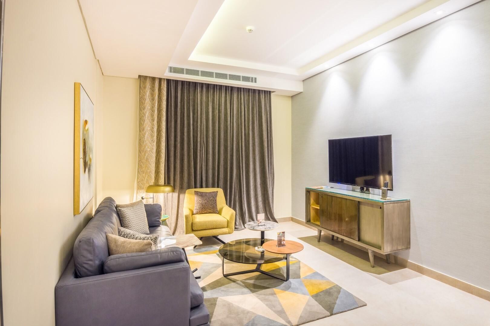 Uma sala de estar moderna com sofá, poltrona, mesa de centro e televisão.
