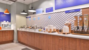 Um balcão de café da manhã moderno com diversas opções de cereais, estação de café e placa indicando o início do café da manhã.