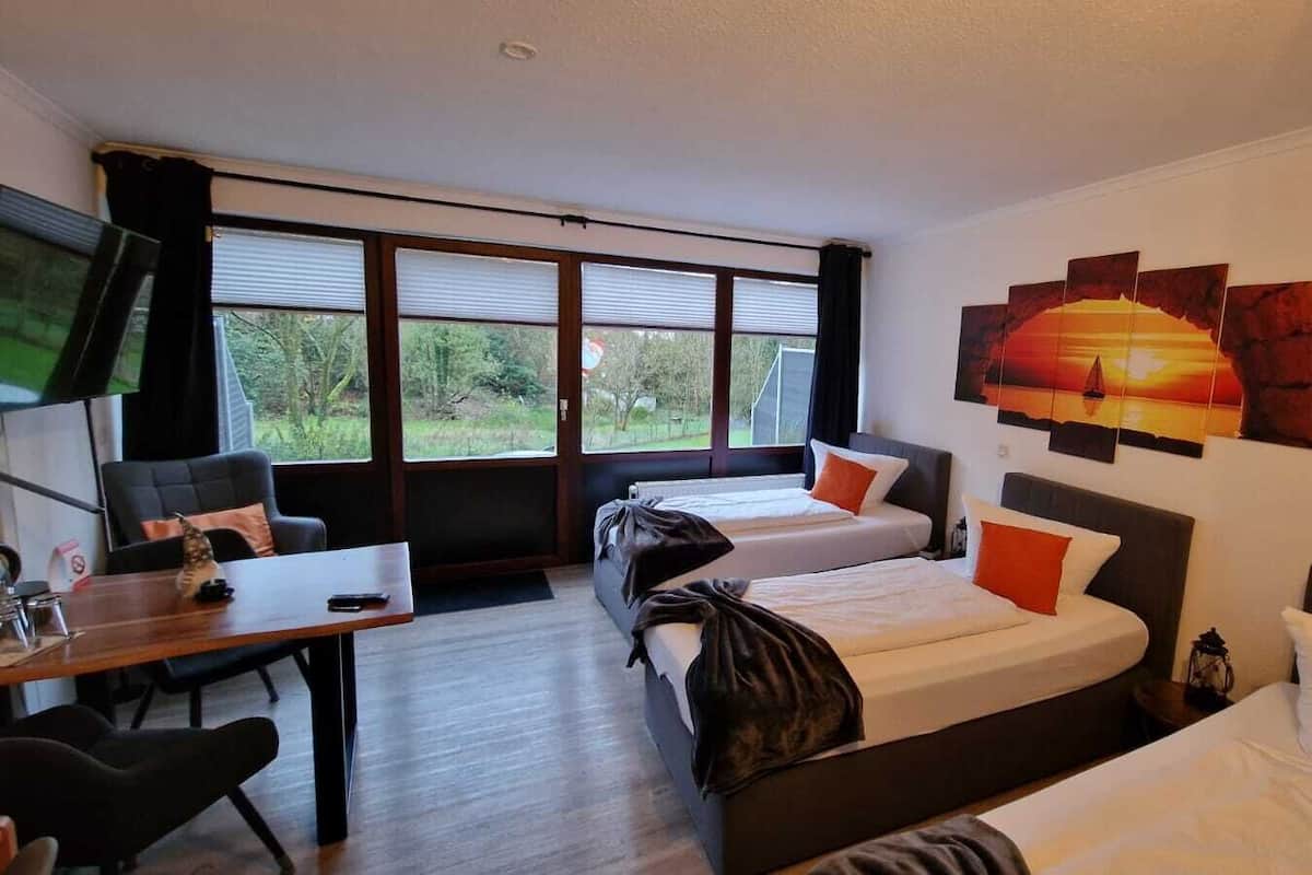 Quarto de hotel com duas camas, uma escrivaninha e uma cadeira.