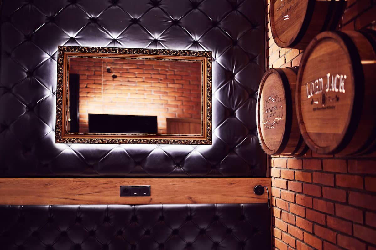 Um quarto com painel de couro acolchoado, uma moldura de madeira e um espelho.
