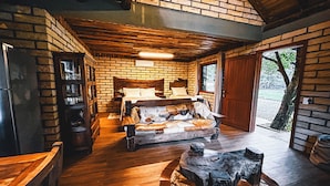Um quarto rústico com uma cama de madeira, uma lareira de pedra e uma janela grande.
