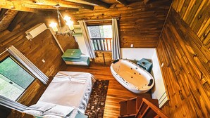 Quarto de cabana de madeira com cama, banheira e janela.
