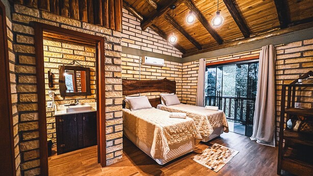 Um quarto aconchegante com teto de madeira, parede de tijolos e uma grande janela.