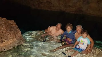 Um grupo de pessoas sentadas em um ambiente semelhante a uma caverna, com água cristalina.