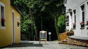 Um caminho de pedras que leva a um edifício com fachada amarela e uma placa.
