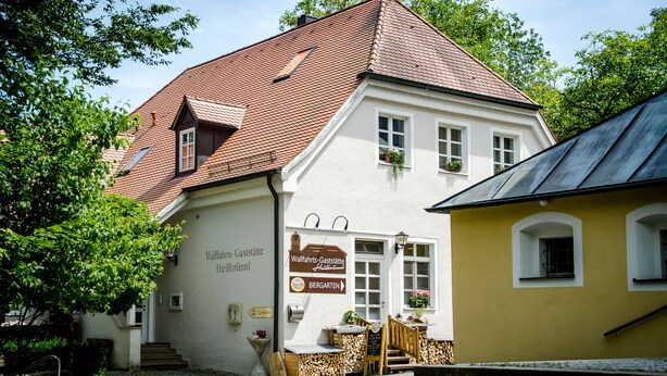 Um edifício tradicional com telhado telhado e um letreiro indicando que é um Biergarten, com uma escadaria que leva à entrada.