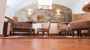 Um interior acolhedor com parede de pedra, lareira e área de jantar com cadeiras e mesa.