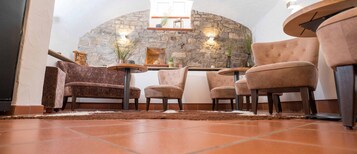 Um interior acolhedor com parede de pedra, lareira e área de jantar com cadeiras e mesa.