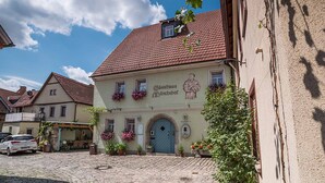 Um edifício europeu tradicional com telhado de azulejos e uma placa indicando que é um restaurante, em frente a uma rua de calçada.