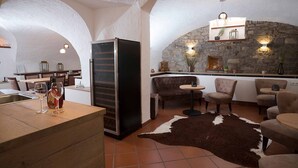 Um interior acolhedor com parede de pedra, móveis rústicos e uma mesa de jantar de madeira com taças de vinho.