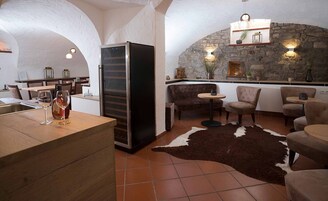 Um interior acolhedor com parede de pedra, móveis rústicos e uma mesa de jantar de madeira com taças de vinho.