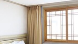 Quarto de hotel com uma janela grande, cortinas e uma cama.